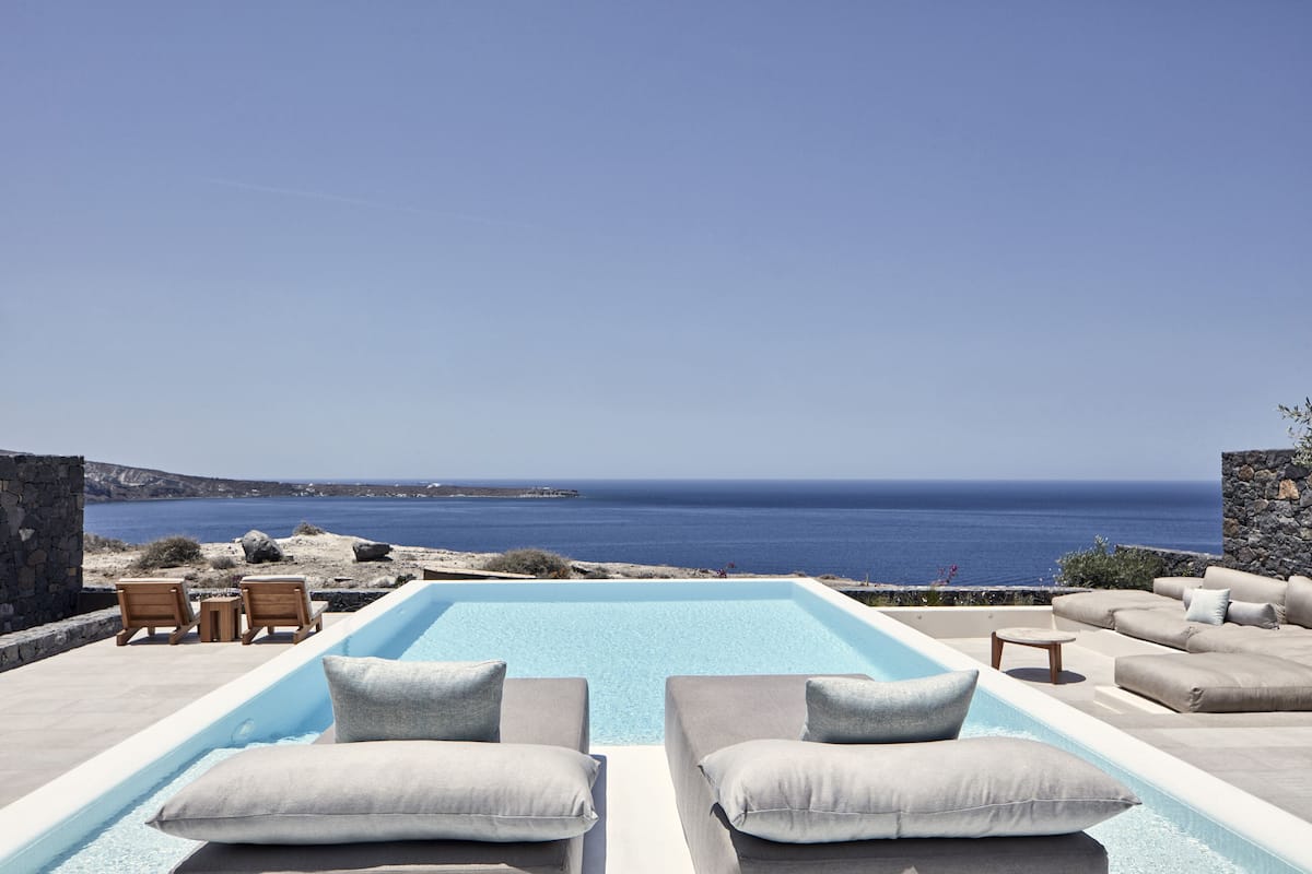 Área na piscina com espreguiçadeiras e vista para o mar.