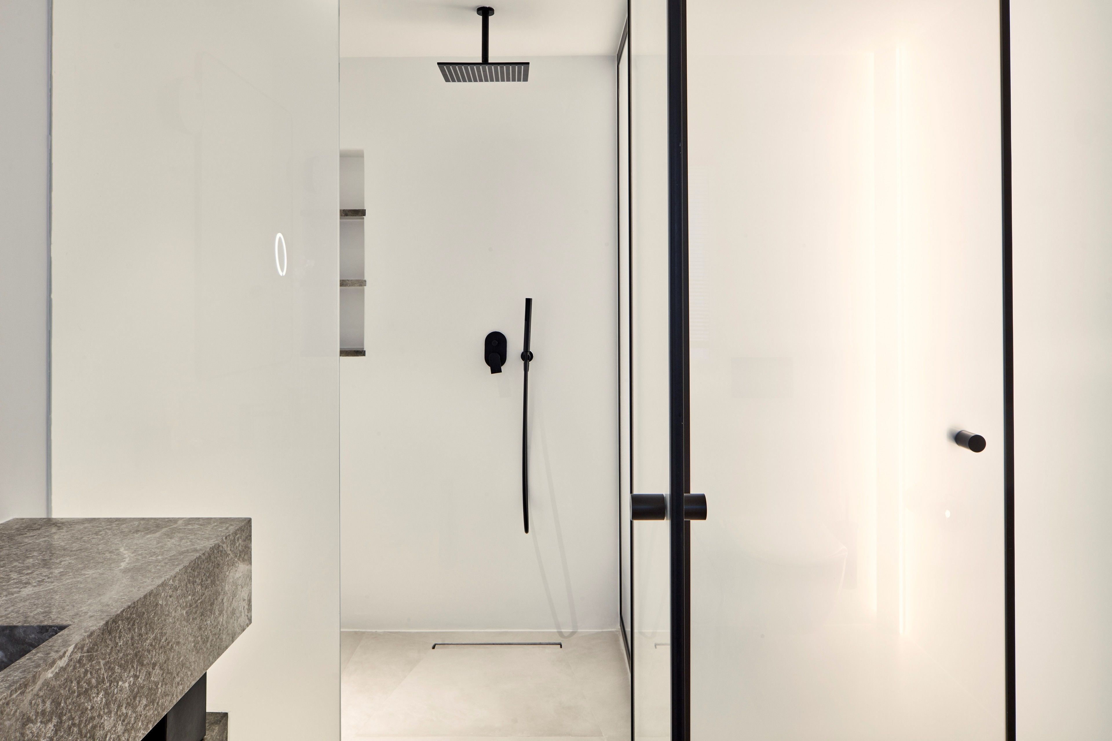 Casa de banho moderna com cabine de chuveiro em vidro, design minimalista e chuveiro à mostra.