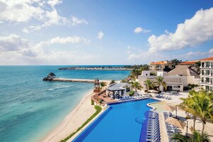 Um resort com piscina grande, praia e vista para o mar.
