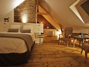Um quarto de sótão aconchegante com uma cama, uma cadeira e uma mesa.
