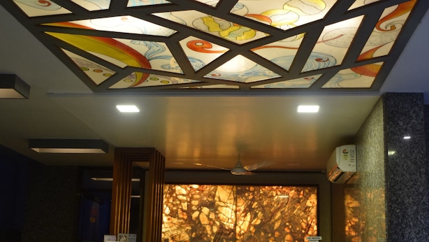 Uma área de recepção com design moderno, destacando um teto estampado e um balcão de mármore.