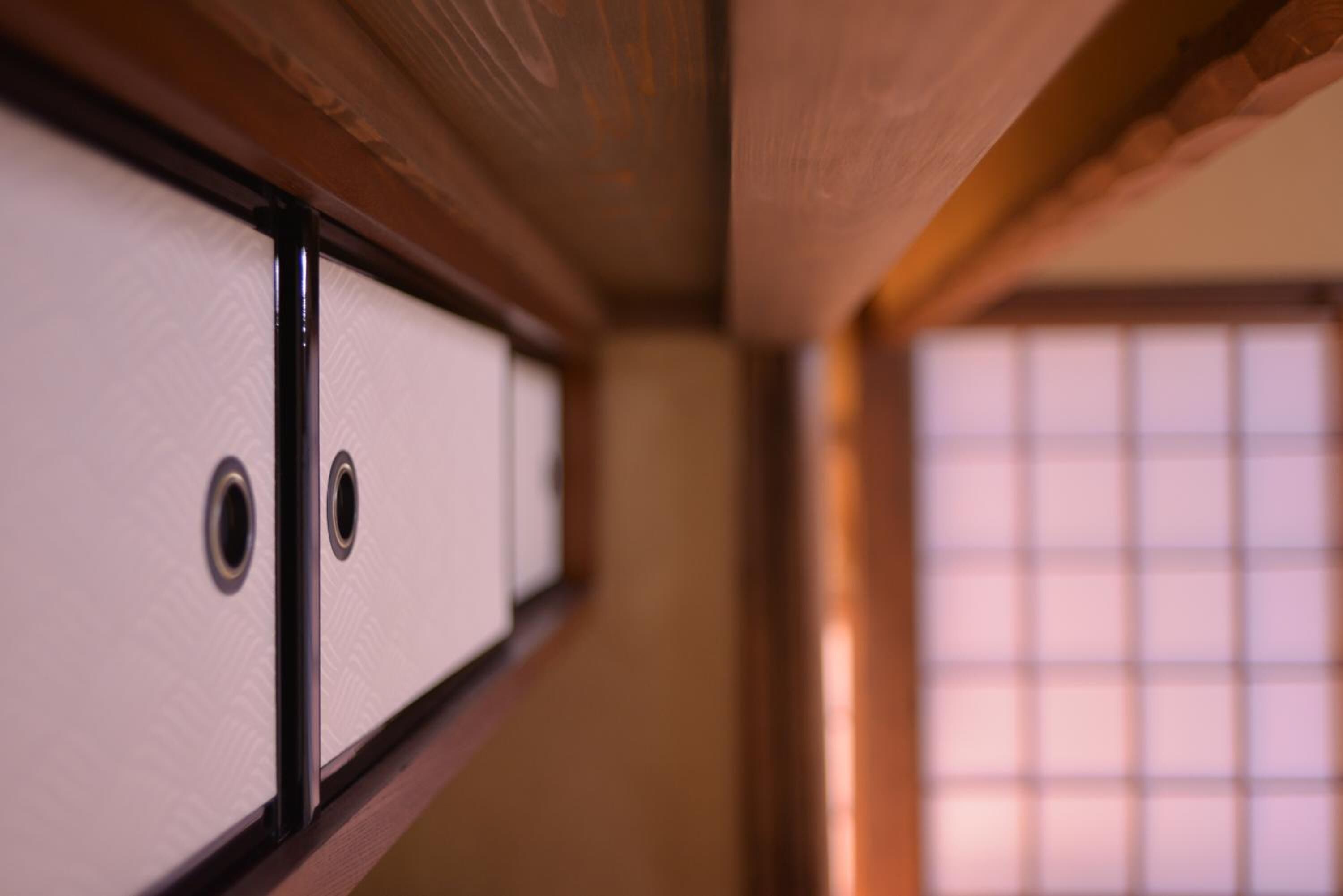 Canto de um quarto com teto de madeira e janela com padrão de grade.