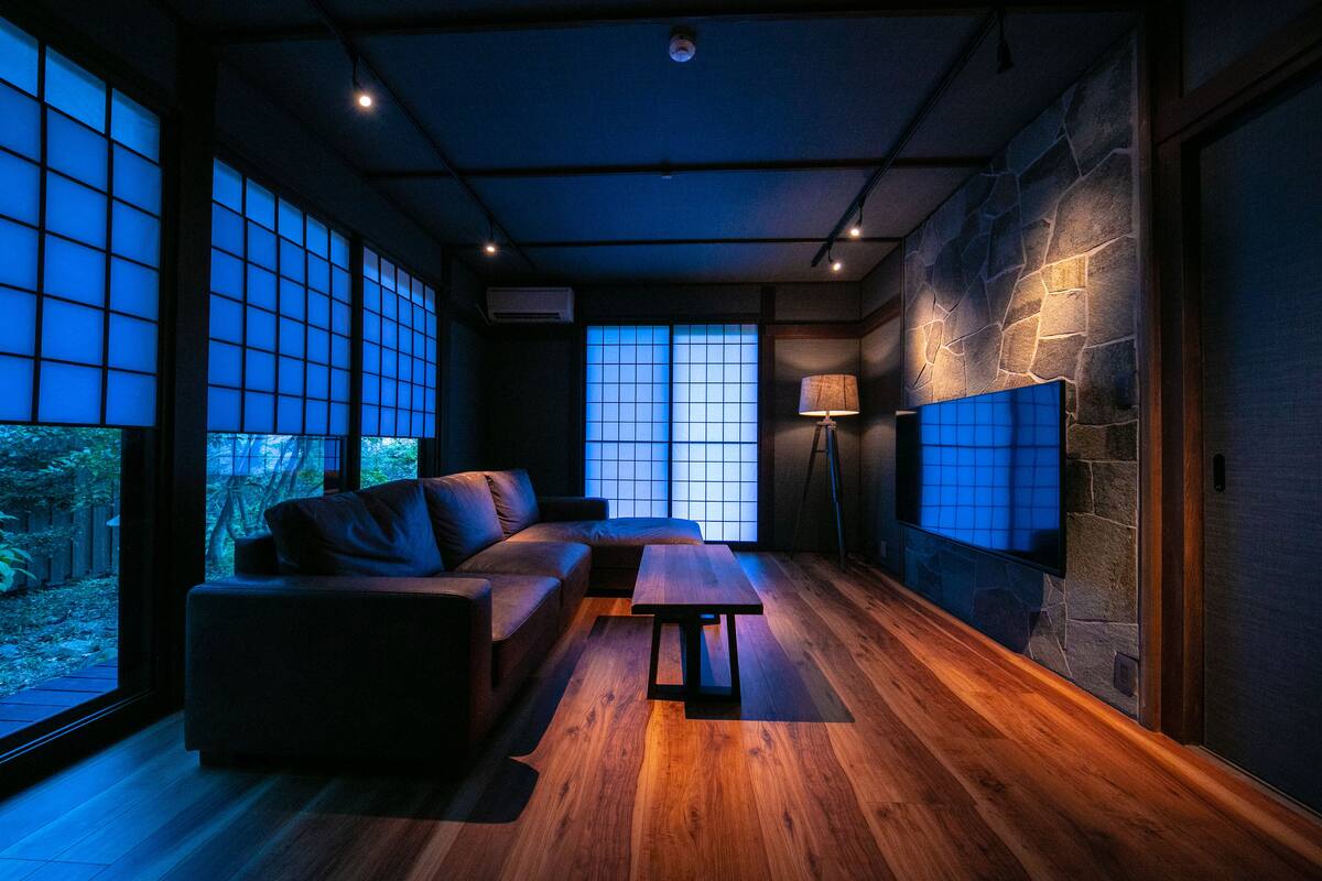 Um interior moderno com soalho de madeira, um sofá, uma mesa e janelas amplas.