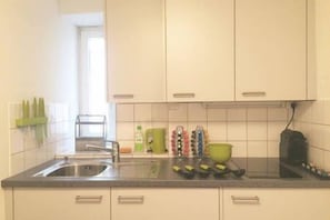 Uma cozinha com armários brancos, pia e diversos utensílios e eletrodomésticos.