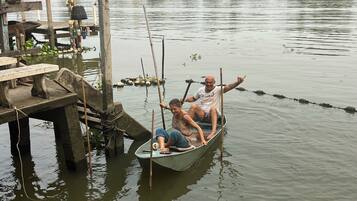 Um cais de madeira com um banco e um pequeno barco com duas pessoas.