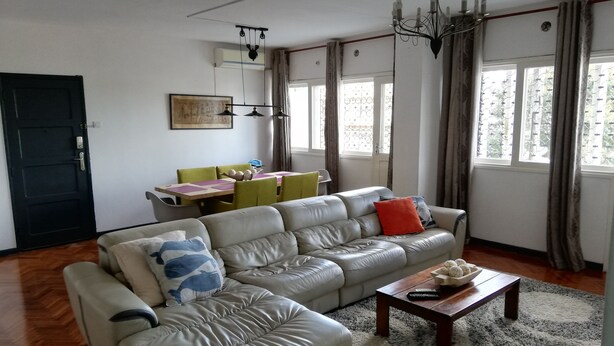 Uma sala de estar com sofá, mesa de centro e um espaço de jantar com cadeiras e mesa.
