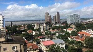 Paisagem urbana com edifícios residenciais, um rio e um grande edifício branco com fachada em grade.