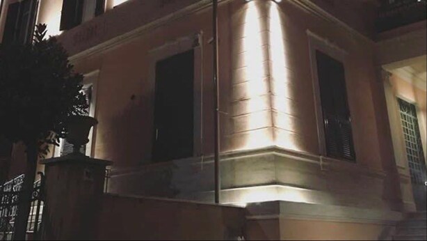 Um edifício com estilo arquitetônico clássico, apresentando uma entrada de canto com uma coluna imponente e uma varanda.