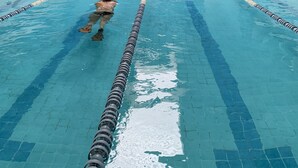 Piscina interna com várias pistas de natação, um mural no teto e assentos para espectadores.