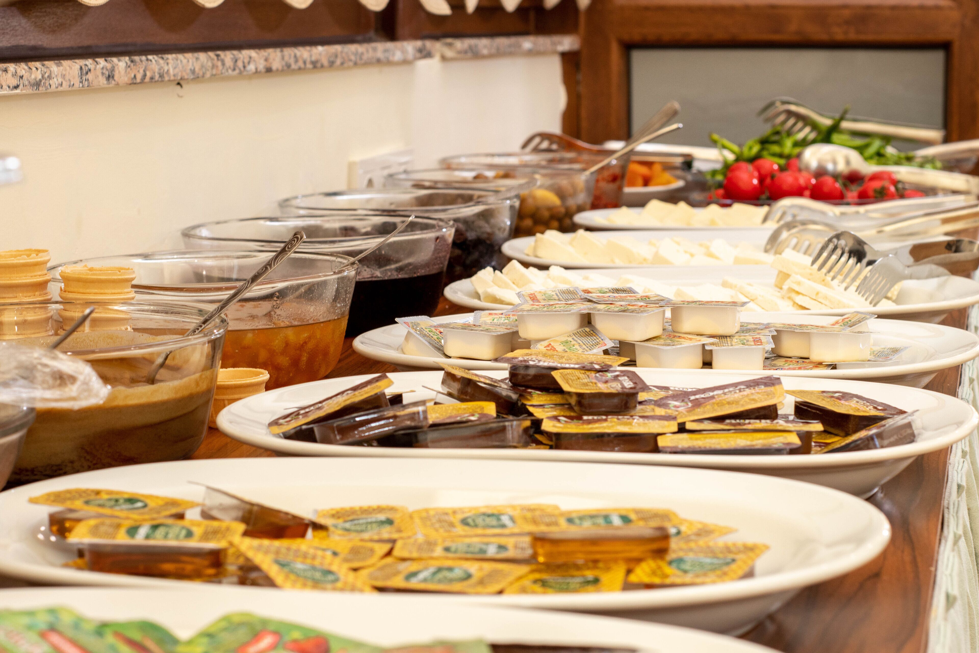 Buffet com diversos itens de comida, incluindo doces, queijos e acompanhamentos.