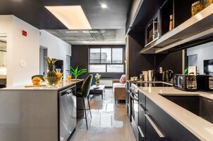 Uma cozinha moderna com ilha central, área de refeições e uma grande janela que proporciona iluminação natural.
