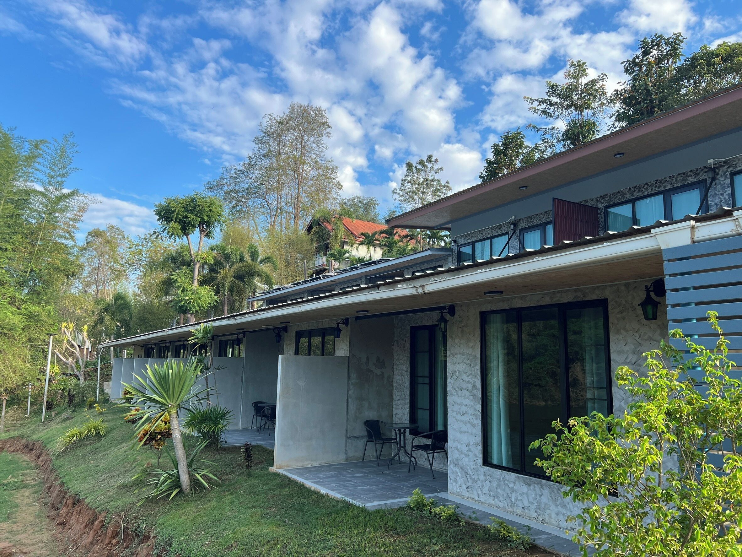 Uma casa moderna de dois andares com varanda coberta, janelas amplas e fachada de pedra.
