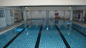 Uma piscina interior ampla com água cristalina e azulejos azuis.