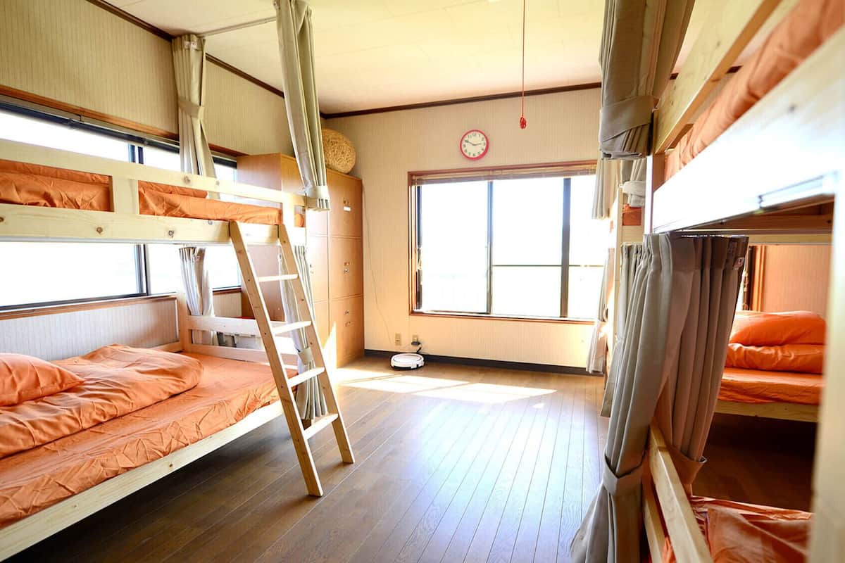 Quarto com beliche, escada, relógio e janela.