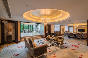 Um hall amplo com um lustre imponente, assentos confortáveis e uma grande janela com vista para o exterior.