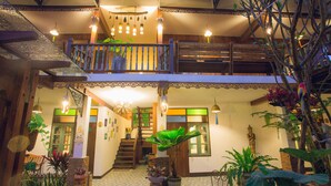 Um interior com vários níveis, escada, plantas em vasos e luminárias pendentes.