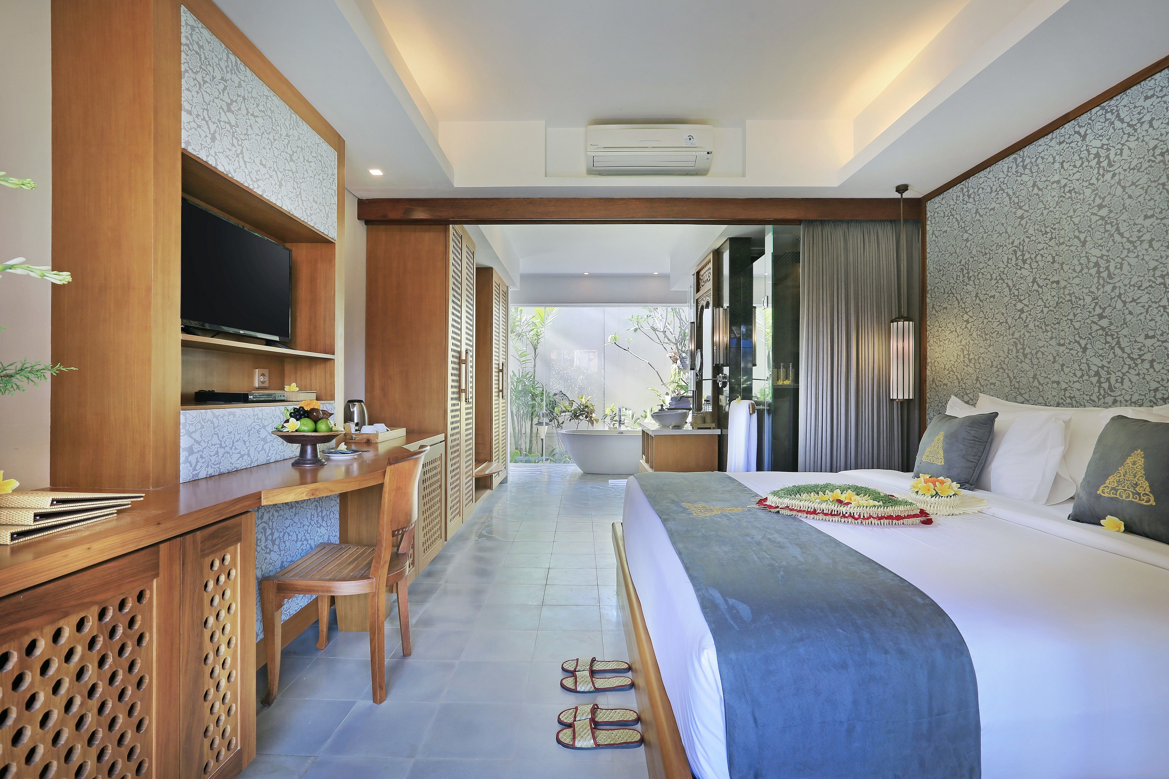 Quarto de hotel com cama, escrivaninha, televisão, banheiro e vista para o exterior.