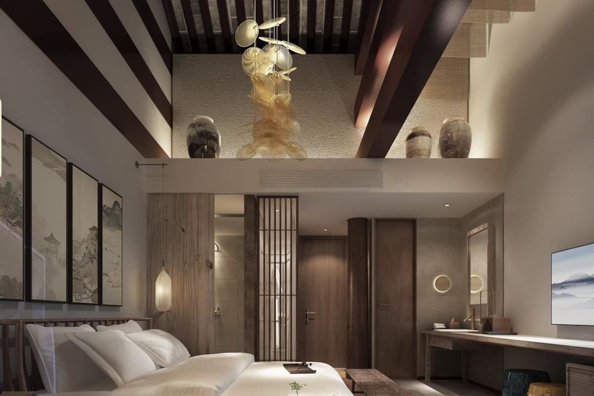 Quarto de hotel moderno com uma cama grande, uma escrivaninha e um espaço para sentar. Há uma janela ampla com vista para a cidade.