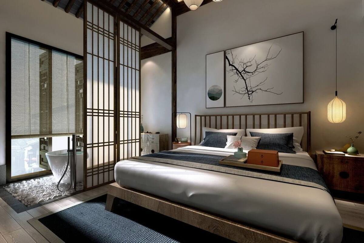 Quarto moderno com cama grande, vigas de madeira e vista para arquitetura tradicional.