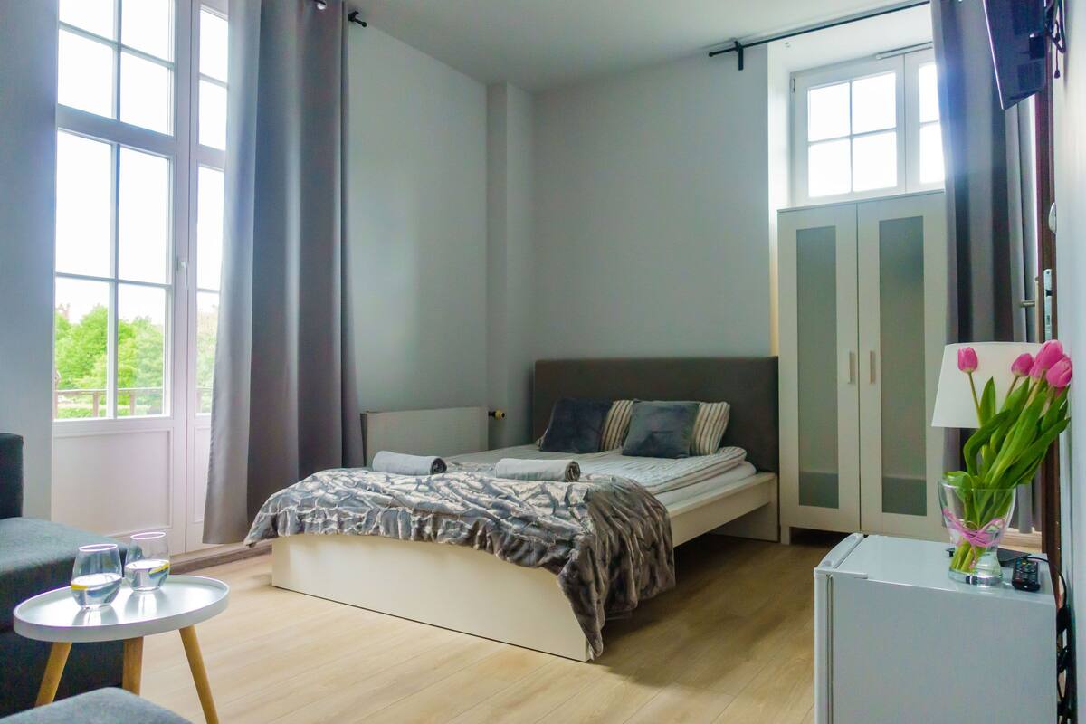 Quarto moderno com cama, mesa de cabeceira e uma pequena mesa redonda.