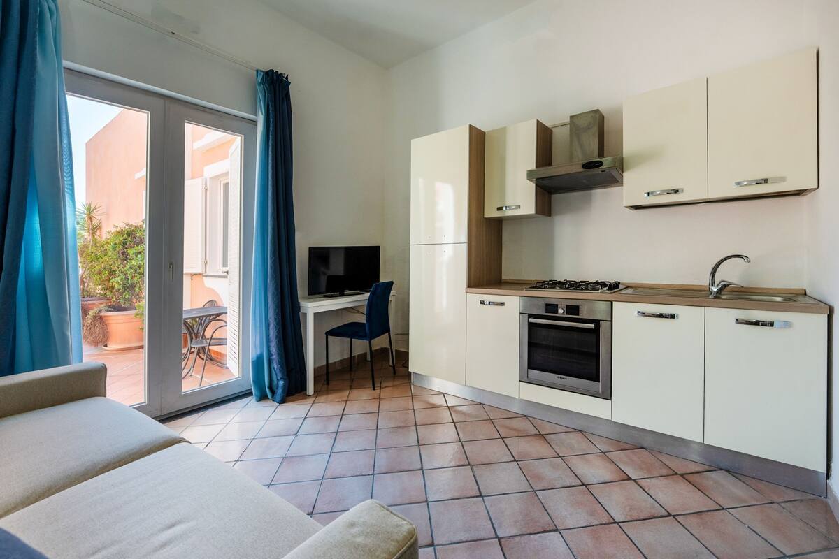 Uma cozinha moderna com área de jantar, televisão e porta de vidro deslizante para um pátio externo.