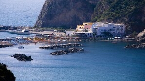Uma vila costeira com um porto, costa rochosa e edifícios com varandas viradas para o mar.
