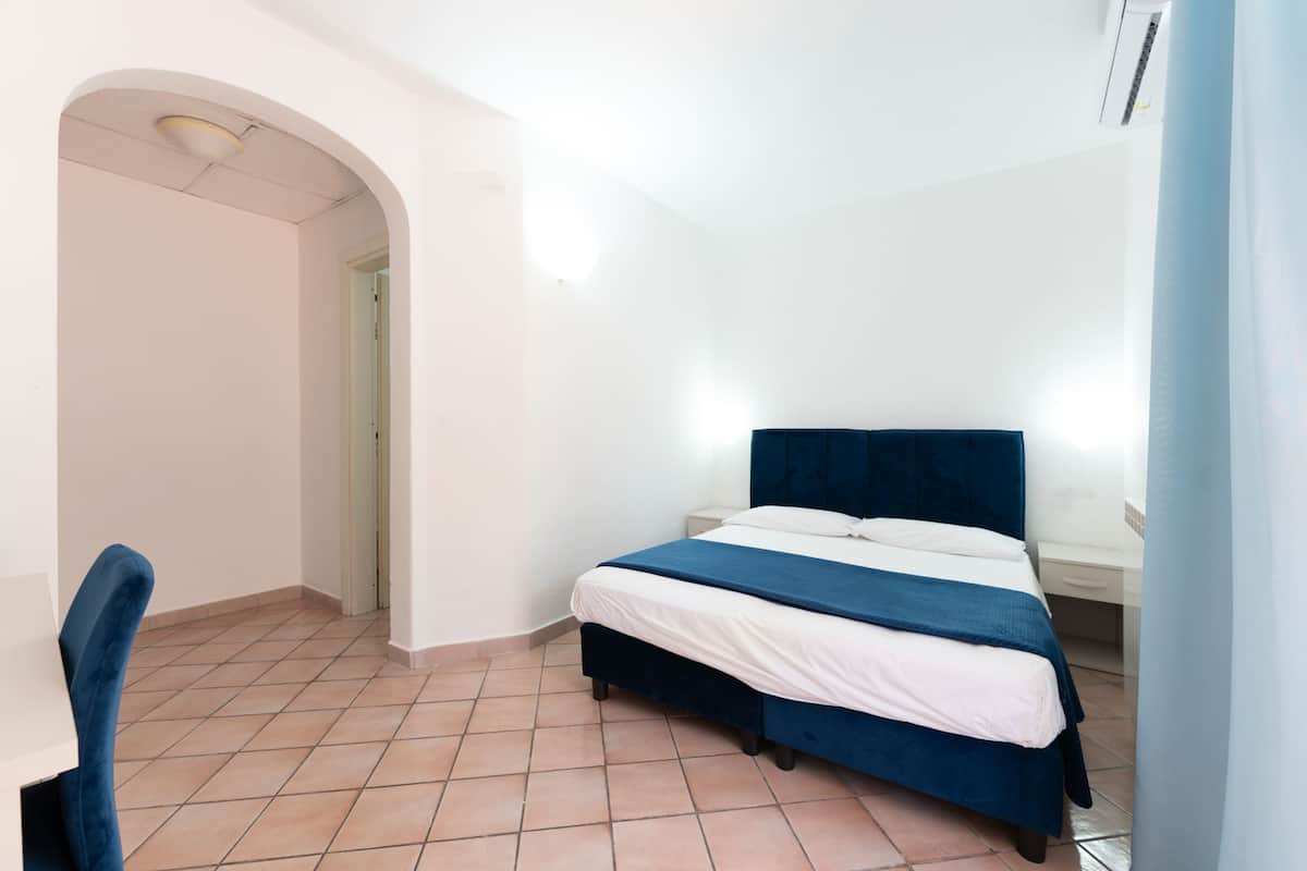 Um quarto com cama, cadeira e escrivaninha.