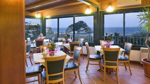 Um restaurante com mobiliário de madeira e amplas janelas com vista para o mar.