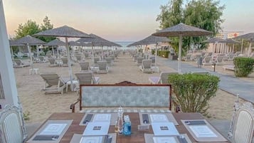 Na praia, espreguiçadeiras, guarda-sóis, bar na praia