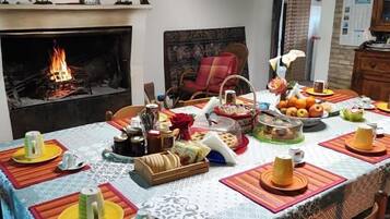 Uma sala de jantar com lareira, mesa posta com pratos, copos e diversos alimentos.