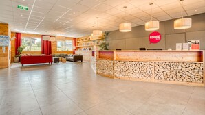 Uma área de recepção moderna com um balcão de madeira, um sofá vermelho e uma grande janela com cortinas vermelhas.