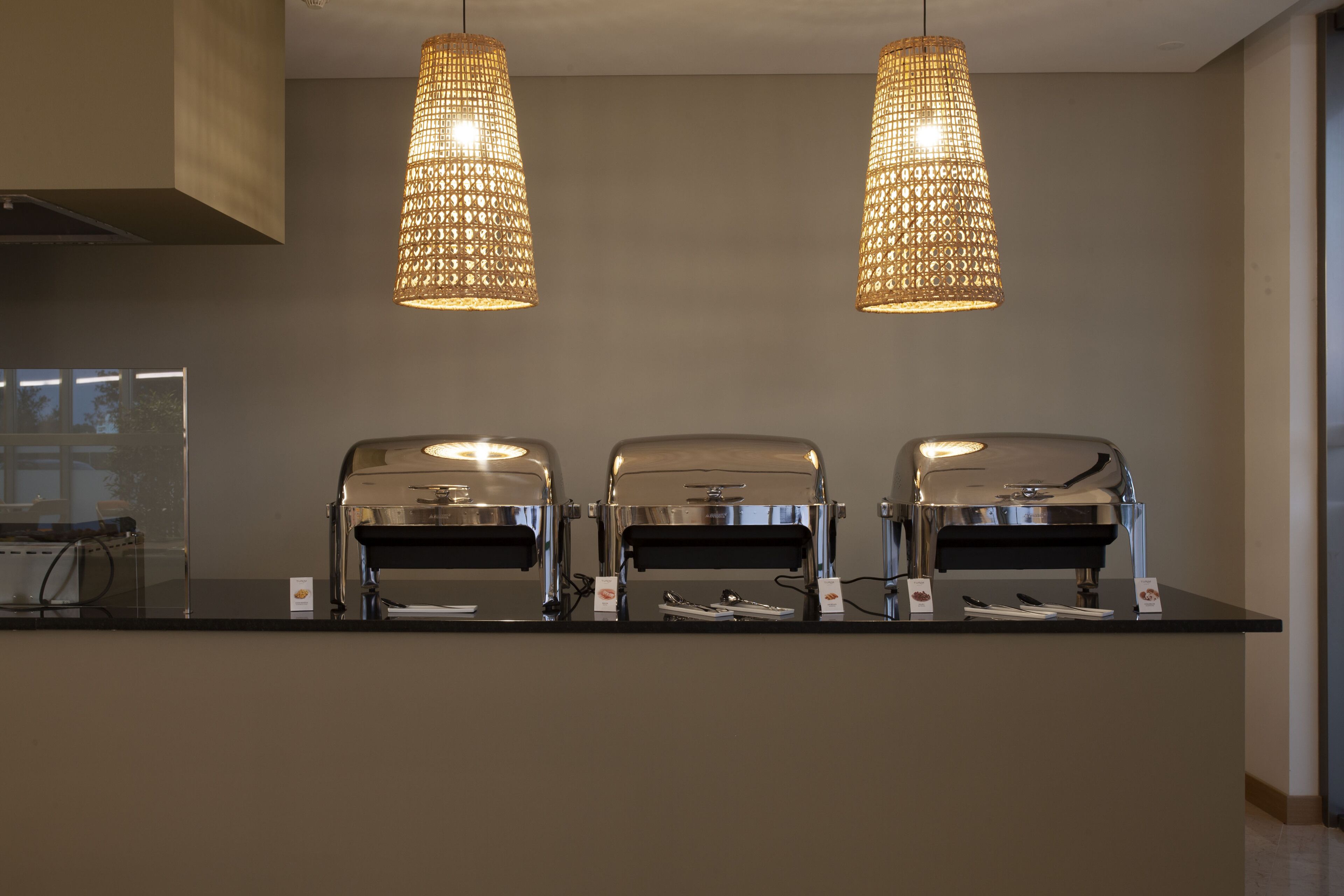 Uma área de cozinha com três máquinas de café expresso e duas luminárias pendentes.