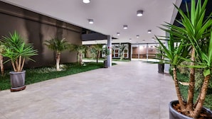 Um corredor moderno com plantas em vasos, iluminação embutida e chão de azulejos limpos.