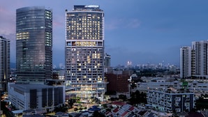 Um hotel imponente em um prédio alto, com uma placa Meridien bem visível, cercado por outros edifícios e uma paisagem urbana ao entardecer.