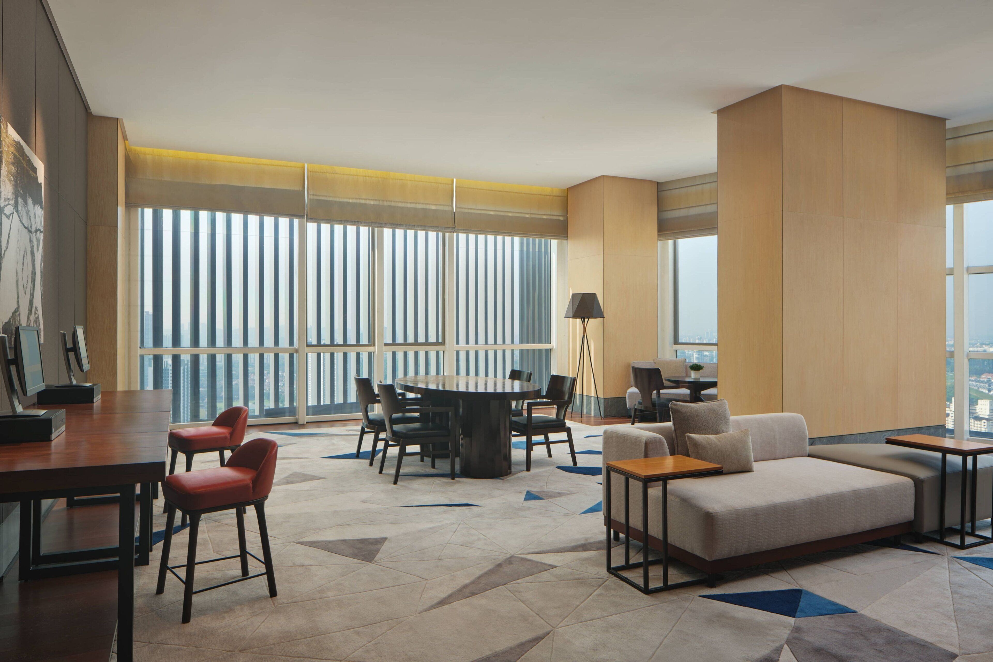 Um hall moderno de hotel com área de refeições, assentos e amplas janelas com vista para a cidade.