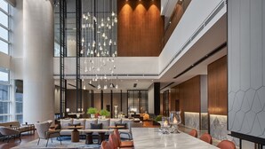 Um hall de hotel moderno com balcão de recepção de mármore, área de estar e um grande candelabro.