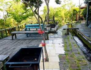 Um deck de madeira com mesas de piquenique e área de churrasco.