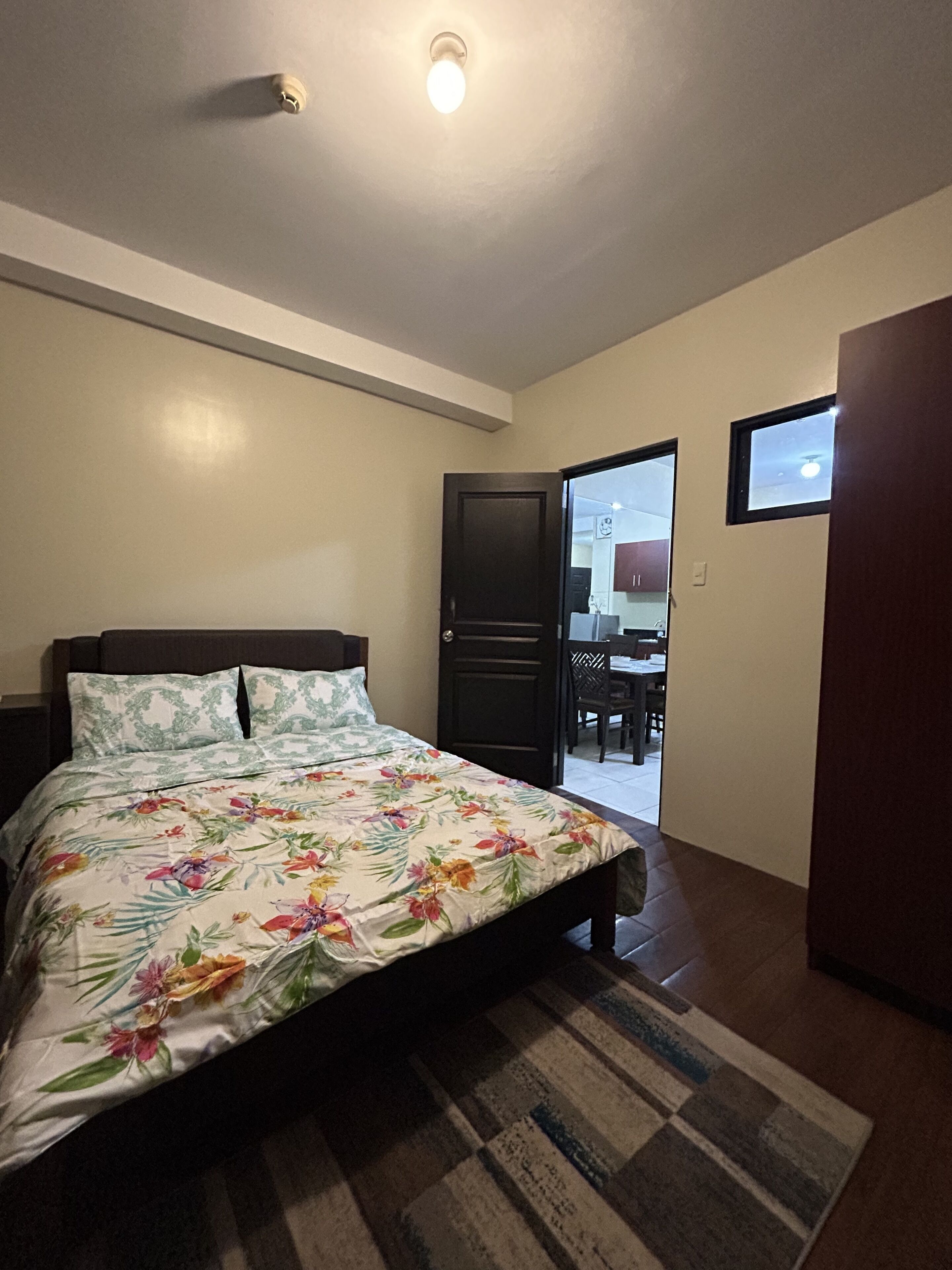 Quarto com cama, porta para uma varanda e uma janela pequena.