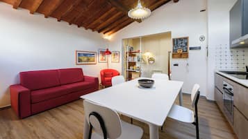 Cozinha moderna com armários brancos, forno embutido e área de refeições com mesa e cadeiras brancas.