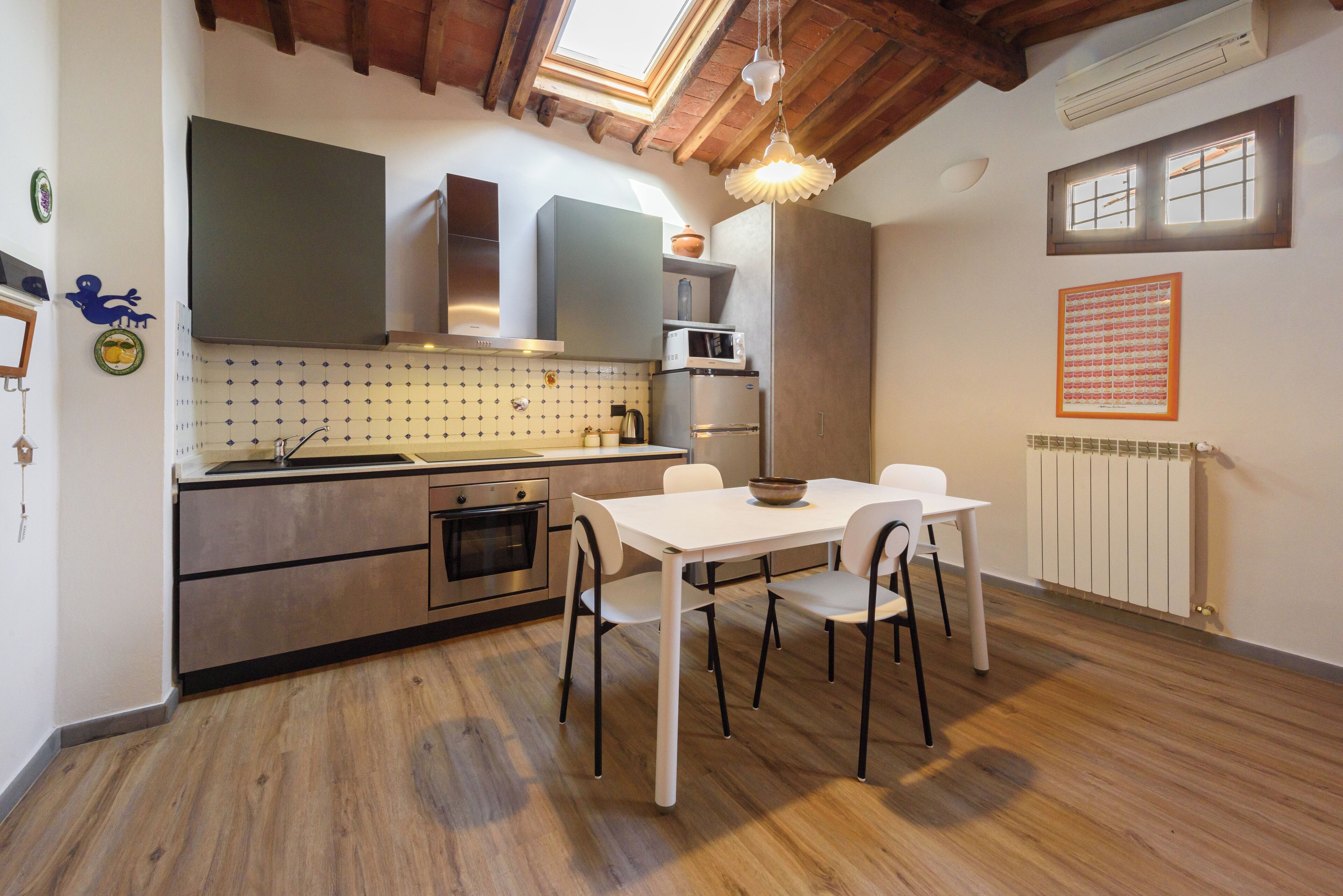 Uma cozinha moderna com área de jantar, piso de madeira e claraboia.
