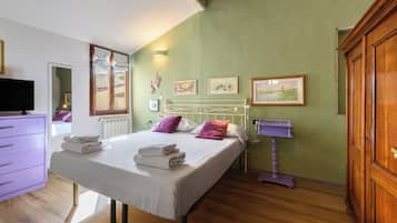 Quarto bem arrumado com uma cama, cômoda, penteadeira e televisão.