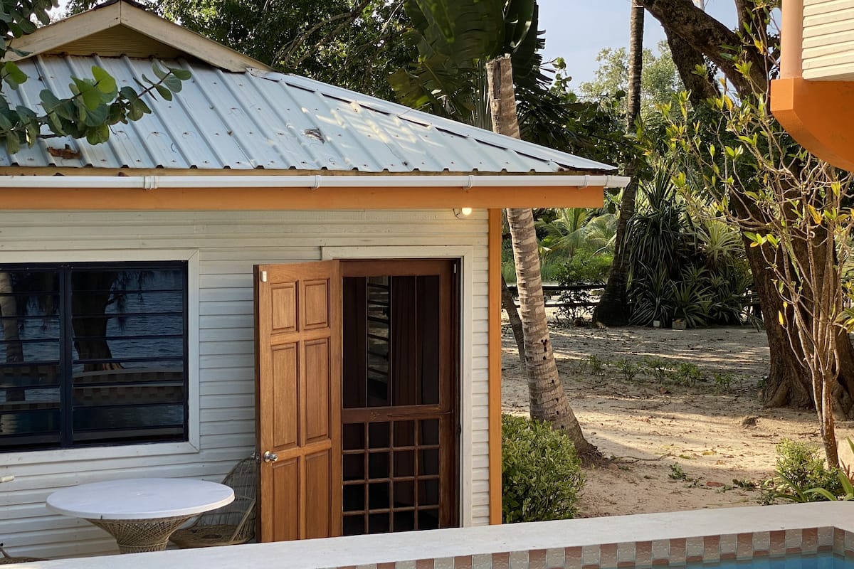 Área de piscina com porta de madeira, uma mesa pequena e a própria piscina.