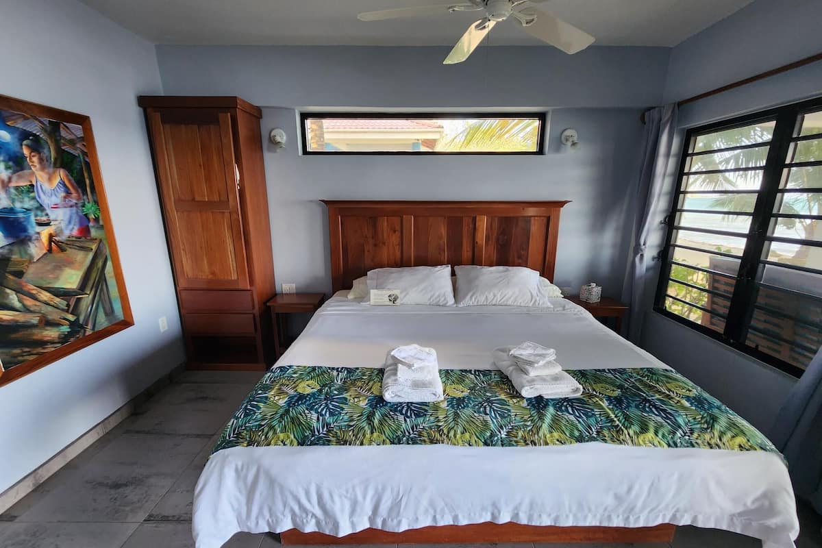 Quarto com cama, ventilador de teto, janela com persianas e um quadro na parede.