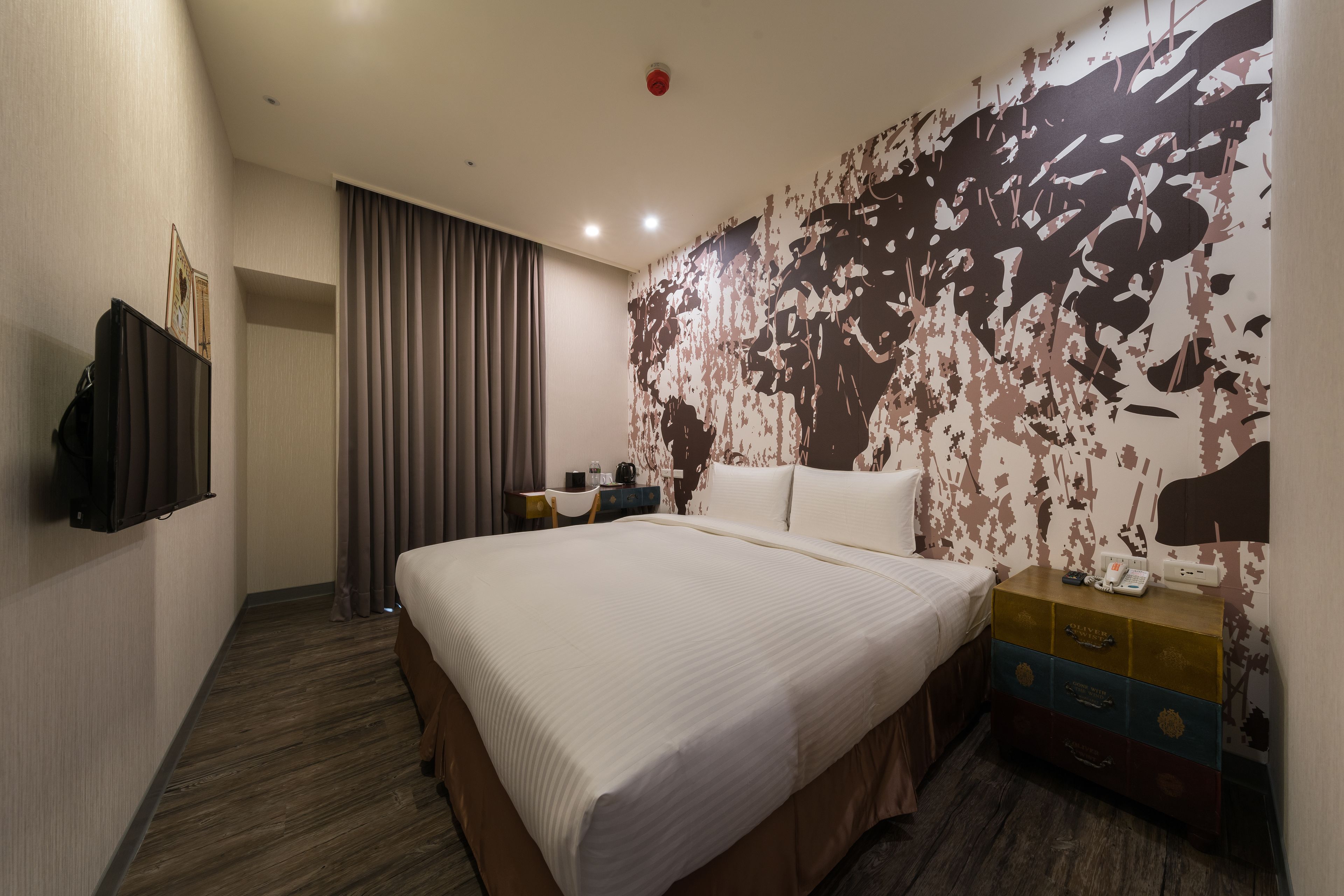 Quarto de hotel com uma cama grande, uma mesa de cabeceira, um penteado, uma televisão e uma cortina.