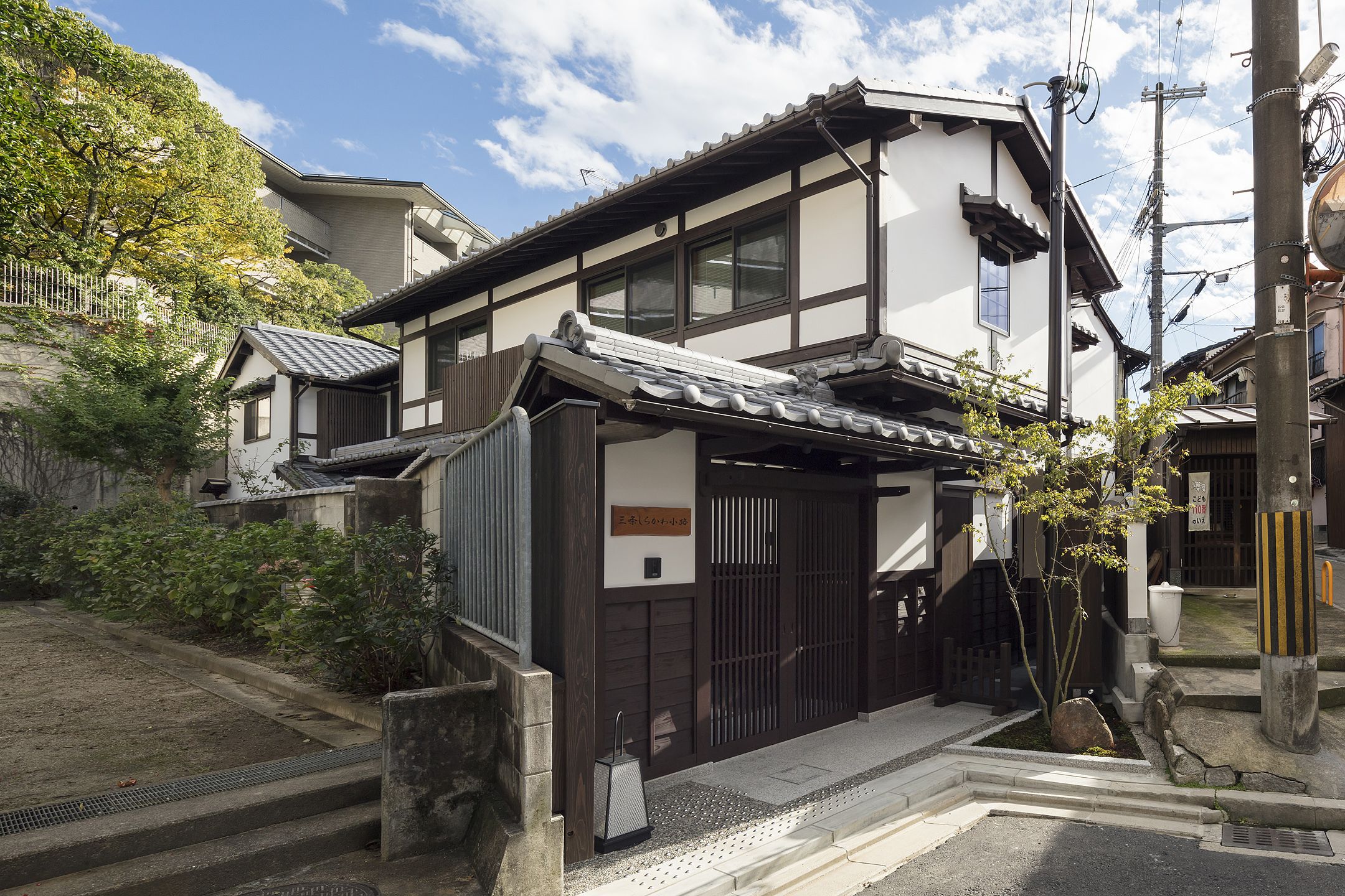 Uma casa tradicional japonesa com fachada de madeira, telhado telhado e um pequeno jardim.