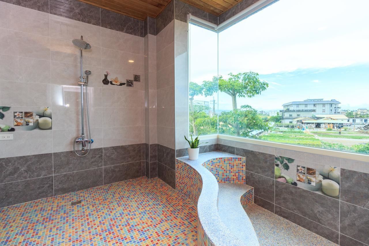 Uma casa de banho moderna com chuveiro, chão em mosaico e vista para o exterior.