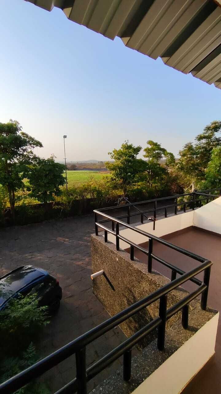 Varanda com vista para uma paisagem verde e um carro estacionado.