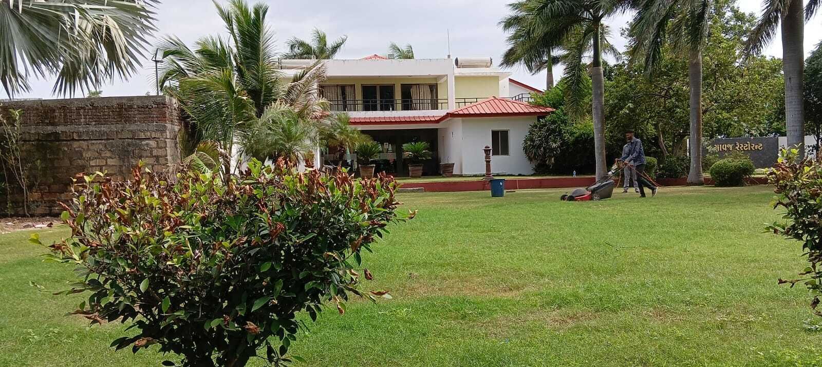 Uma área residencial com uma casa, gramado e uma pessoa cortando a grama.