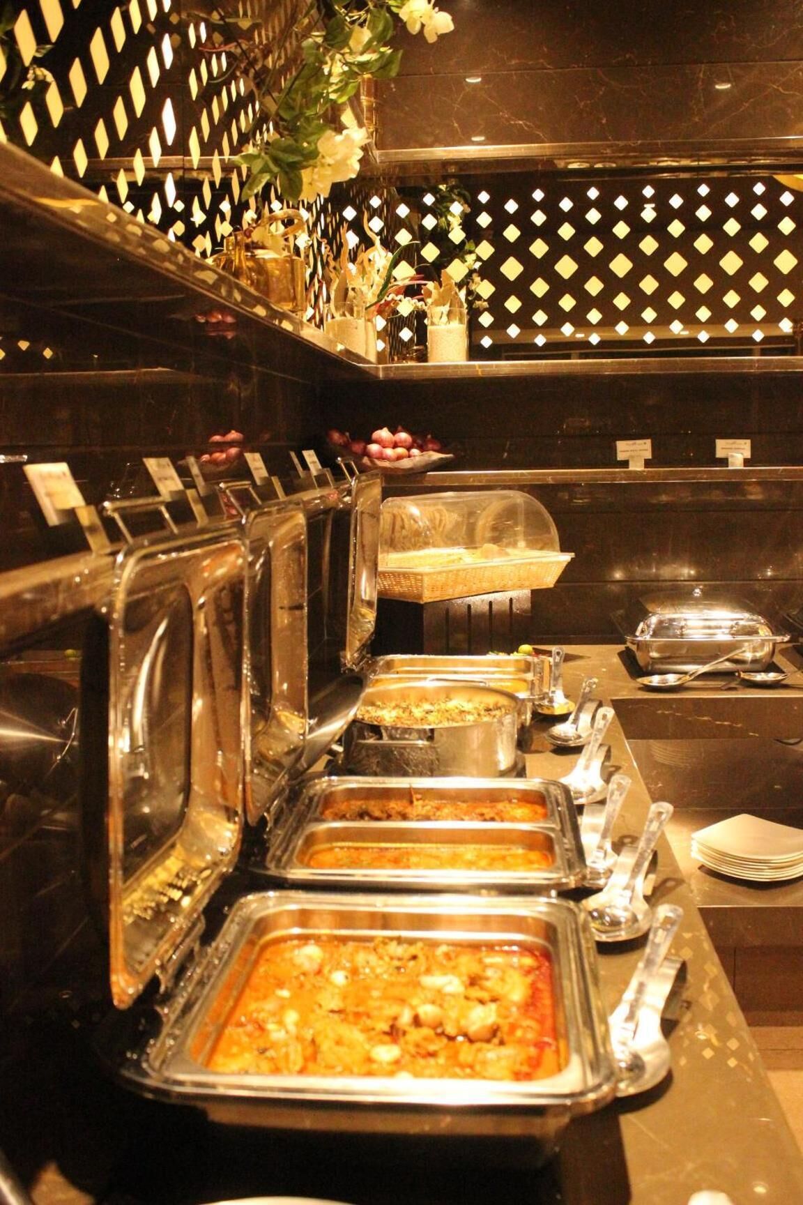 Disposição de buffet com diversas estações de serviço de alimentos, incluindo pratos de massa e outras opções.