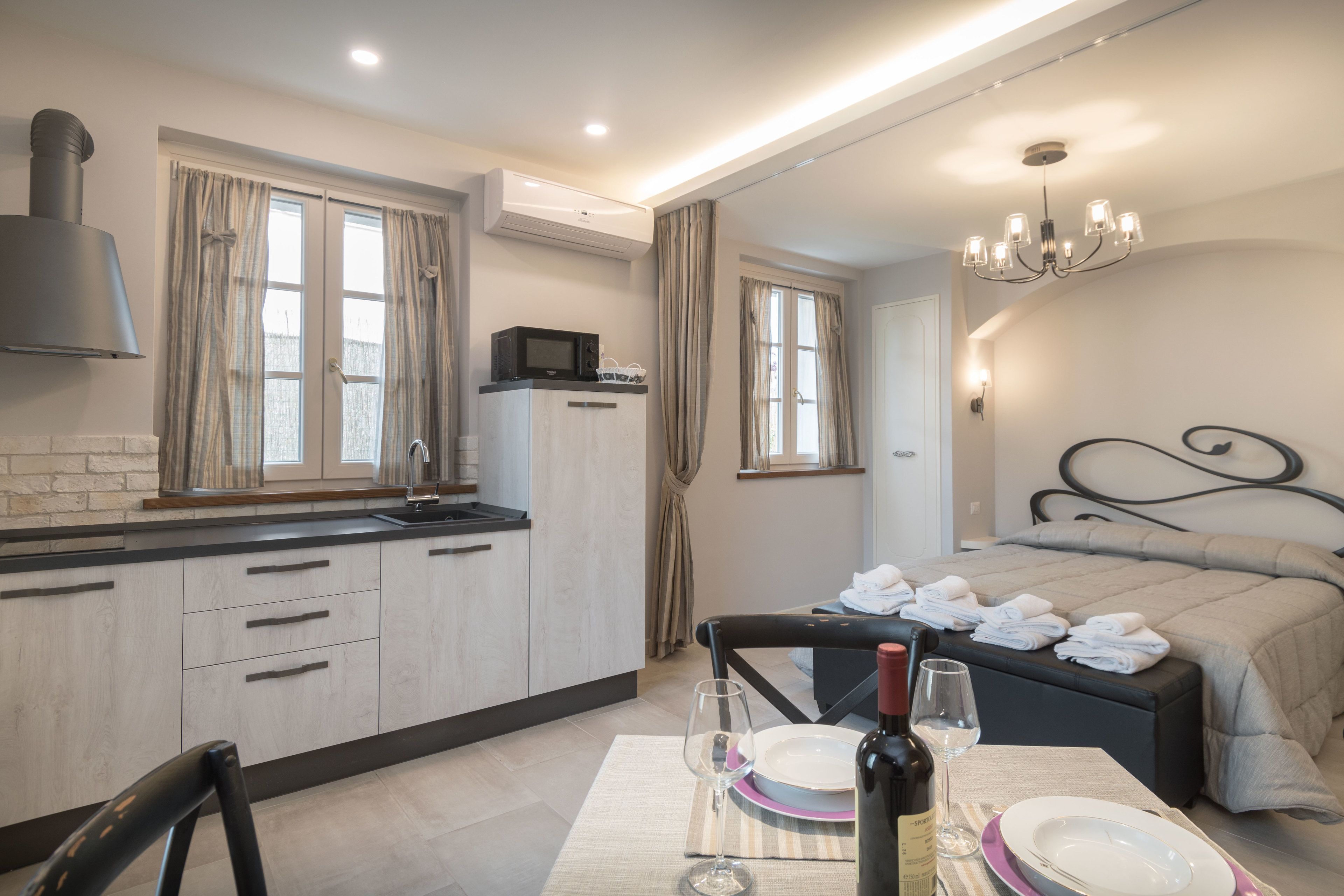 Quarto de hotel moderno com cozinha, área de jantar e uma cama.